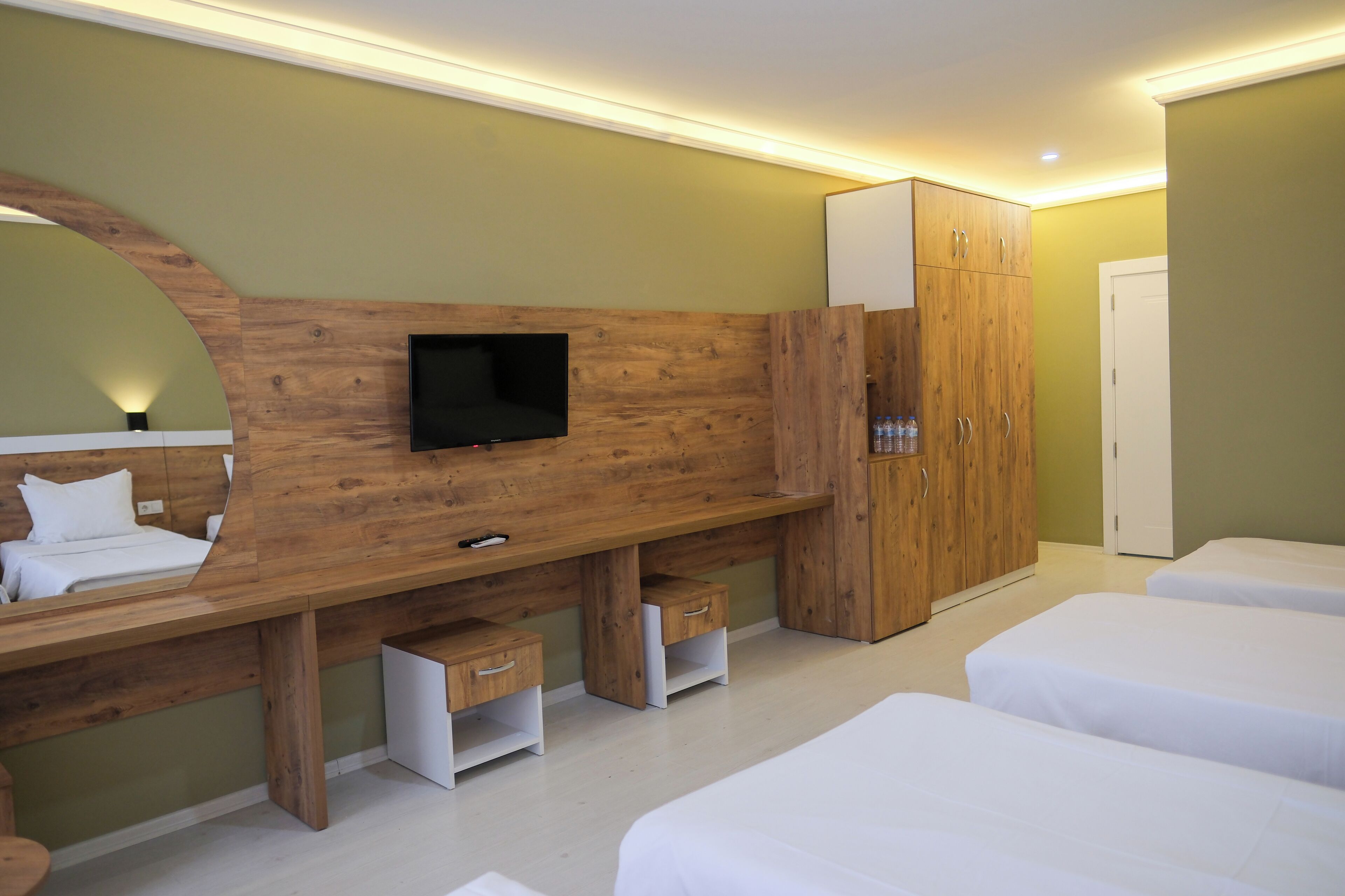 Quarto de hotel com escrivaninha de madeira, televisão de tela plana, guarda-roupa e duas camas.