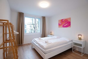 Quarto com uma cama, duas mesas de cabeceira, uma janela e uma escada de madeira.