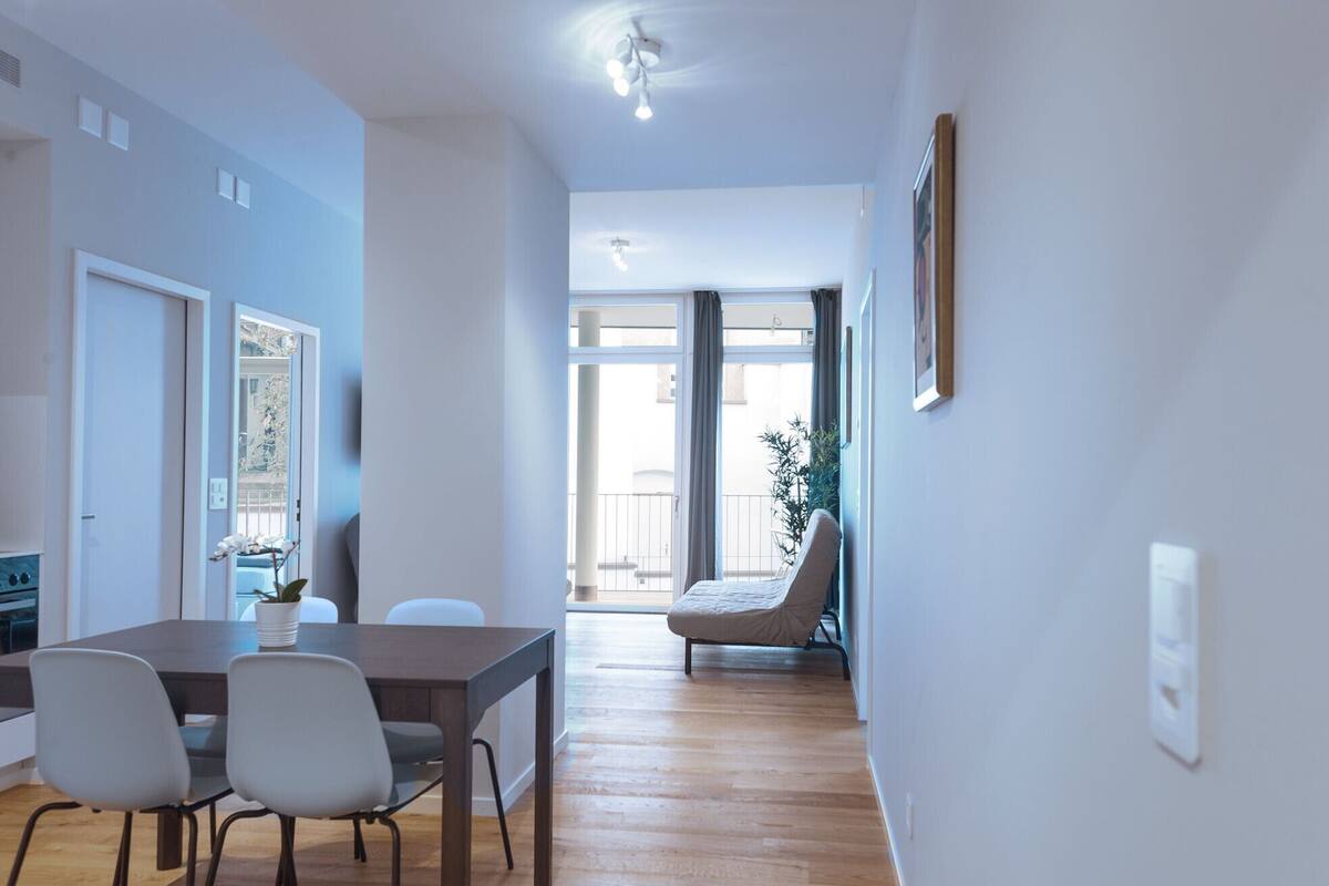 Uma sala de estar moderna com área de jantar, sofá e vista para o exterior.