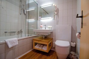 Um banheiro com banheira, pia, vaso sanitário e espelho.