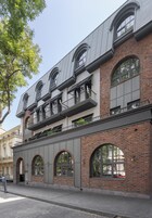 Um edifício de vários andares com fachada de tijolos, janelas arqueadas grandes e varandas.