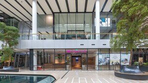 Um edifício moderno com fachada de vidro, um letreiro chamativo para Crowne Plaza e uma área de piscina em primeiro plano.