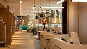 Um hall de hotel moderno com balcões de mármore, mesa de recepção e área de estar.