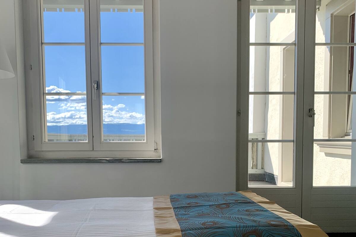 Quarto com duas camas, janela com vista para o céu e porta que dá para uma área externa.