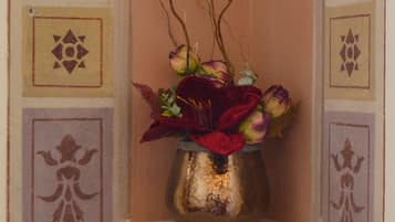 Parede com painéis decorativos e uma pequena prateleira com um vaso de flores.