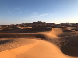 Paisagem desértica com dunas de areia e céu claro.