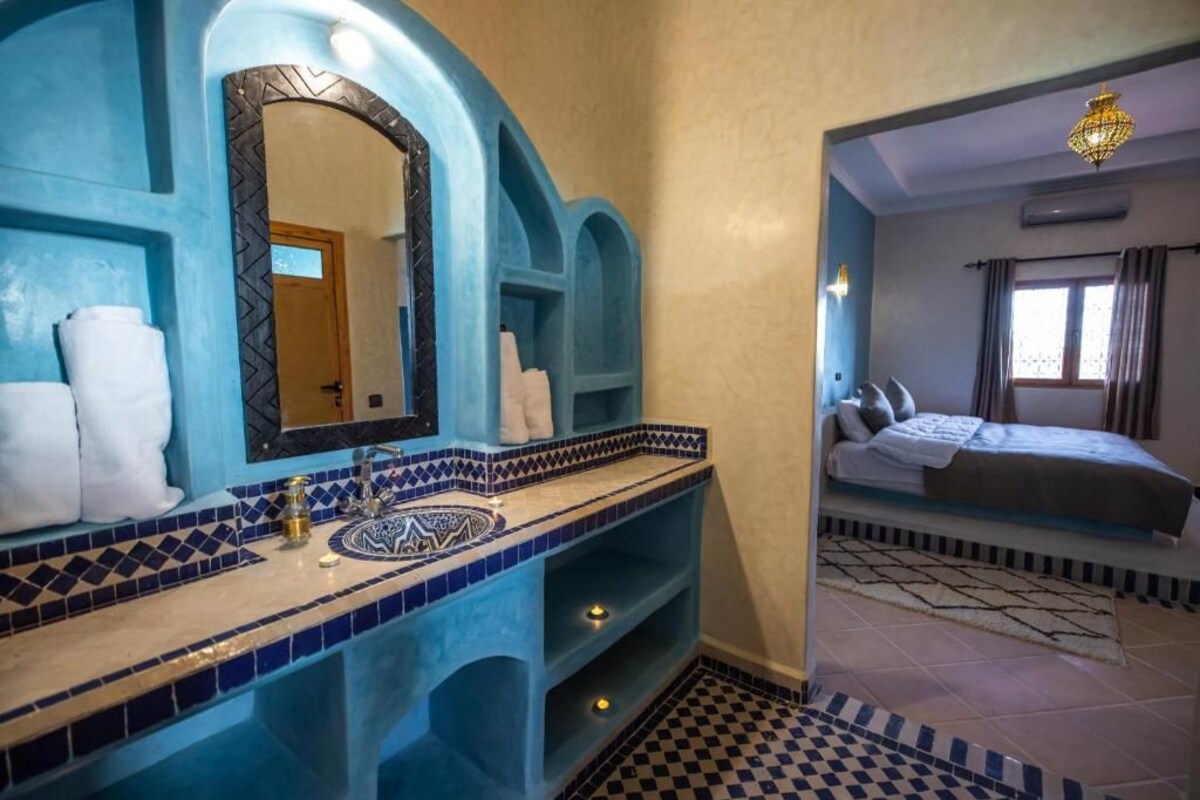 Casa de banho com lavatório azul, espelho e zona de duche.