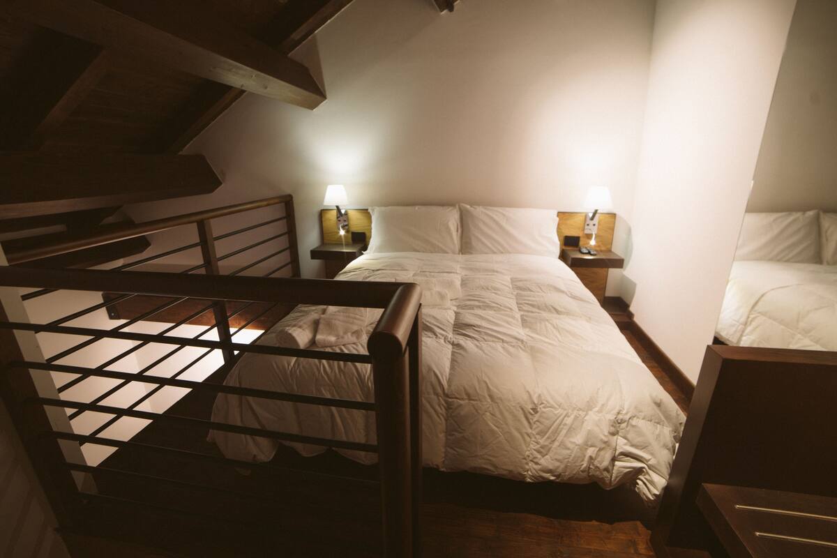 Quarto com estrutura de cama de madeira, uma cama de solteiro e uma mesa de cabeceira com abajur.