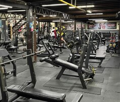 Uma academia com diversos equipamentos de exercícios, incluindo bancos e aparelhos de musculação.
