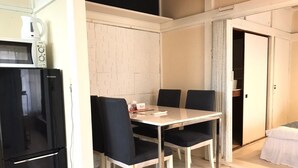 Quarto compacto com cozinha compacta, mesa de jantar com cadeiras e cama.