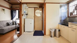 Um espaço compacto para viver, com cozinha compacta, sofá, radiador e uma pequena lixeira.