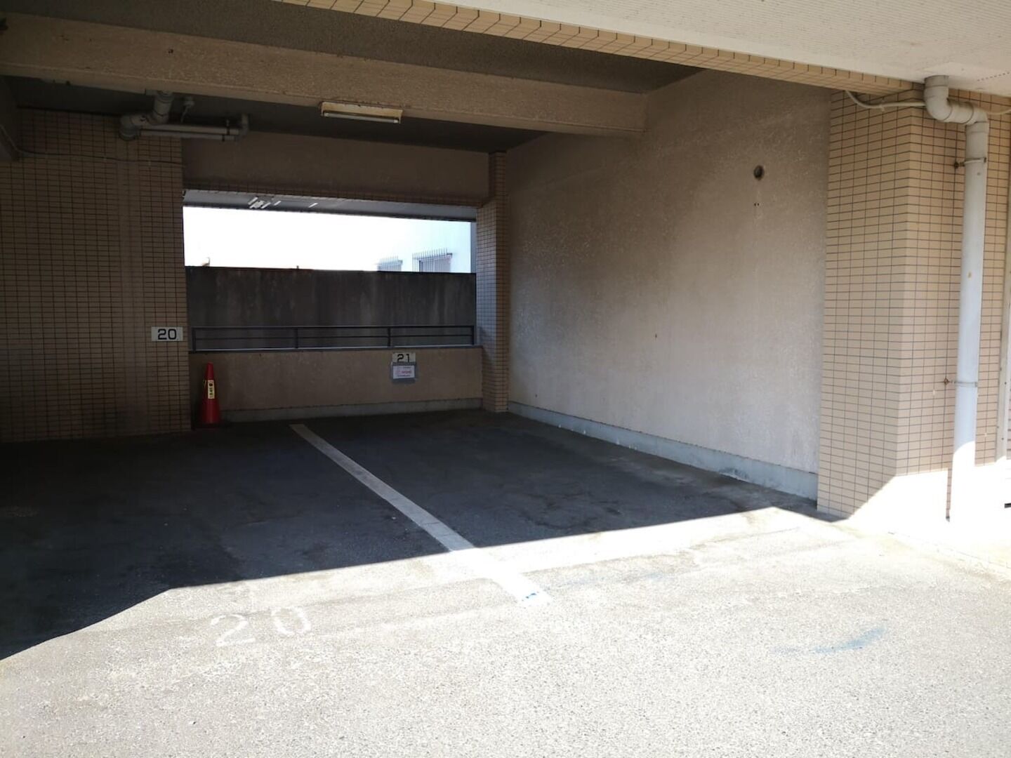 Garagem de estacionamento vazia com vagas numeradas, extintor de incêndio e janela visível.