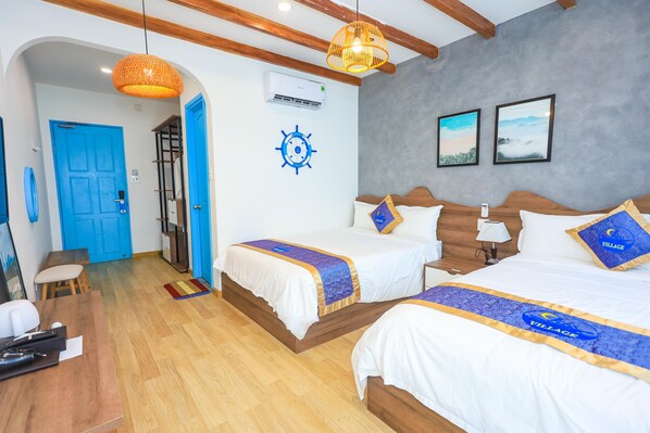 Quarto de hotel com duas camas, cabeceiras de madeira, porta azul, ar condicionado fixado na parede e ventoinha no teto.
