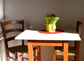 Uma mesa com um jogo americano vermelho, um jarro amarelo e um recipiente verde com um objeto vermelho em cima.