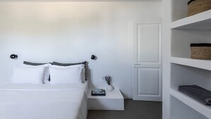 Quarto minimalista com cama, mesas de cabeceira e guarda-roupa.