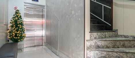 Um lobby moderno com uma escadaria de mármore, uma árvore de Natal e um elevador.