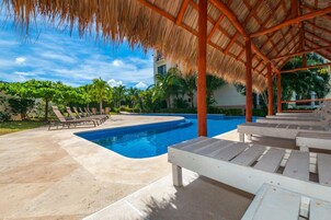 Uma área de piscina com espreguiçadeiras e uma estrutura de telhado de palha.