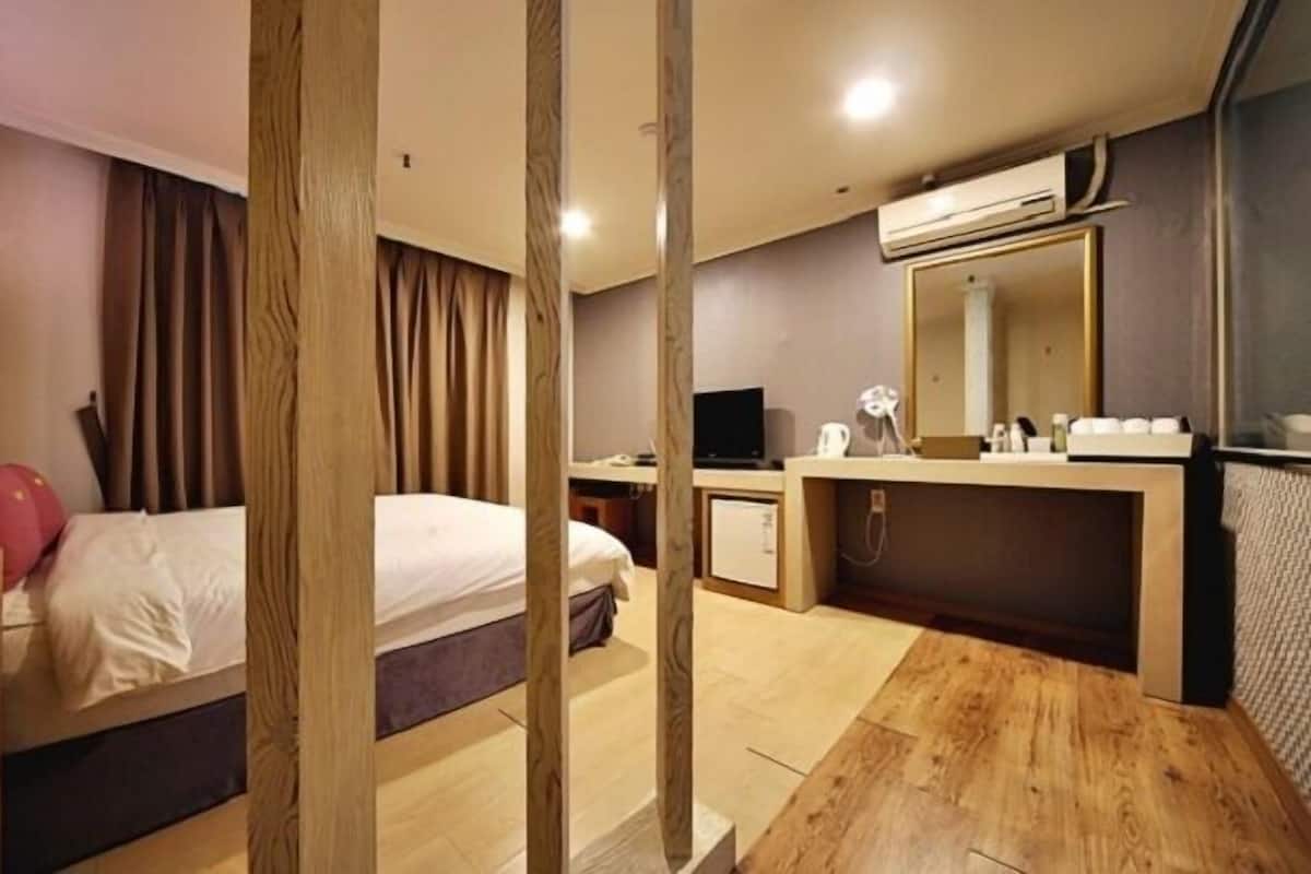 Quarto de hotel com duas camas, uma mesa com computador, um espelho e um aparelho de ar condicionado.
