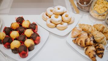 Diversos pastéis sobre uma mesa, incluindo donuts, croissants e outros produtos de panificação.