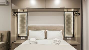 Quarto de hotel moderno com uma cama grande, duas mesas de cabeceira, uma cabeceira e uma janela com mosquiteiro.