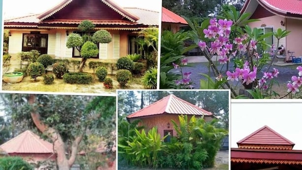 Um edifício tradicional com telhado em cerâmica, rodeado por jardins bem cuidados e uma ponte de madeira.