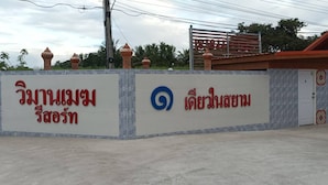 Um edifício com uma placa que diz "Nakhon Sawan" em escrita tailandesa.