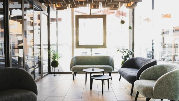 Um interior moderno com um sofá verde, duas poltronas e uma mesa pequena.