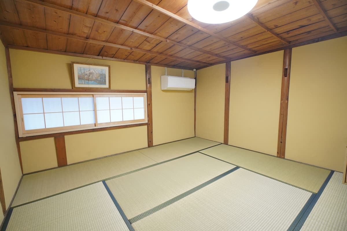 Um quarto japonês tradicional com piso de tatame, teto de madeira e um quadro na parede.