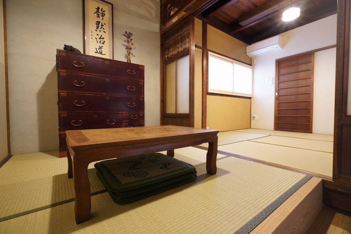 Um quarto japonês tradicional com tatames, uma mesa de madeira, um armário e um biombó shoji.