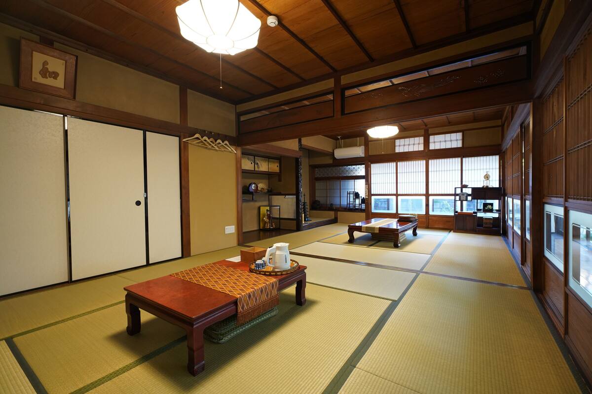 Um quarto japonês tradicional com tatames, uma mesa de madeira baixa e portas deslizantes.