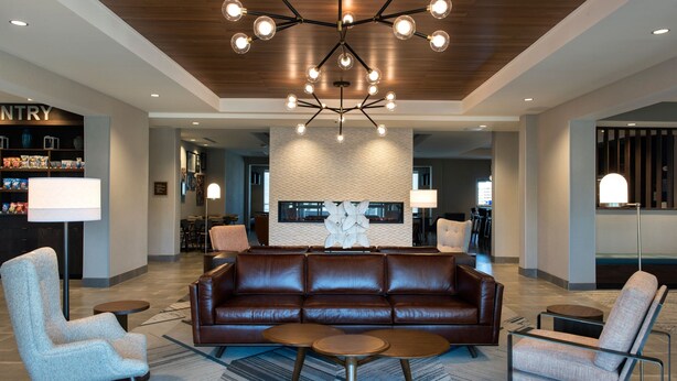 Um lobby moderno com um sofá de couro, poltronas e um candelabro.