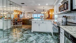 Cozinha moderna com armários brancos, bancada de granito e micro-ondas embutido.