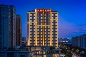 Um hotel moderno e imponente, com várias andares, grandes janelas e uma placa bem visível no topo.