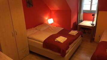 Um quarto com cama, escrivaninha e guarda-roupa.