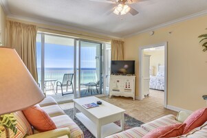 Quarto de hotel com varanda, televisão, sofá e mesa de centro.