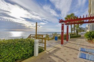 Na praia, areia branca, espreguiçadeiras, guarda-sóis 