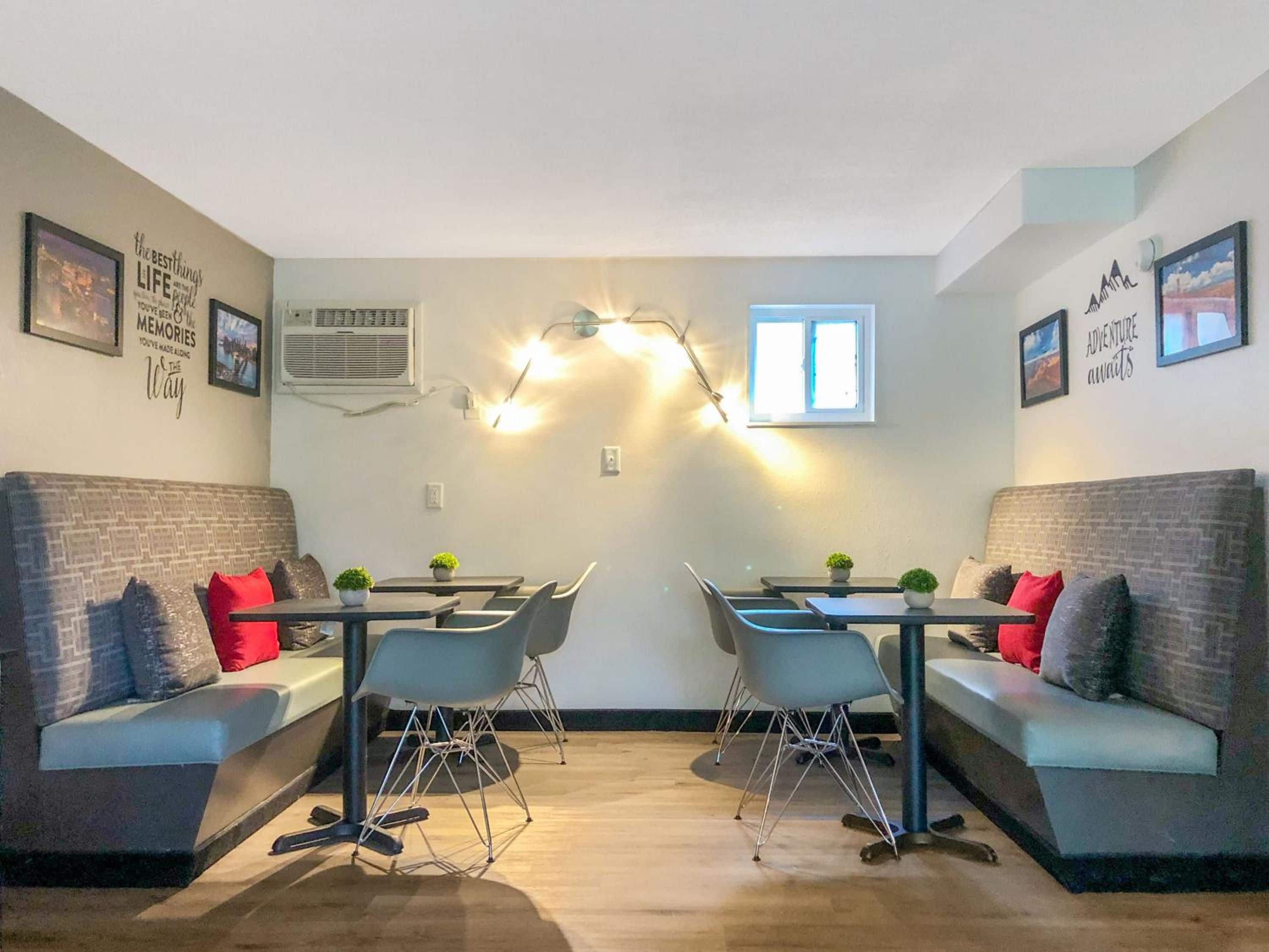 Uma sala de estar moderna com sofá, duas mesas de jantar e cadeiras, uma janela e decorações nas paredes.