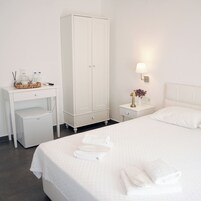 Quarto de hotel com cama, guarda-roupa, mesa de cabeceira e escrivaninha.