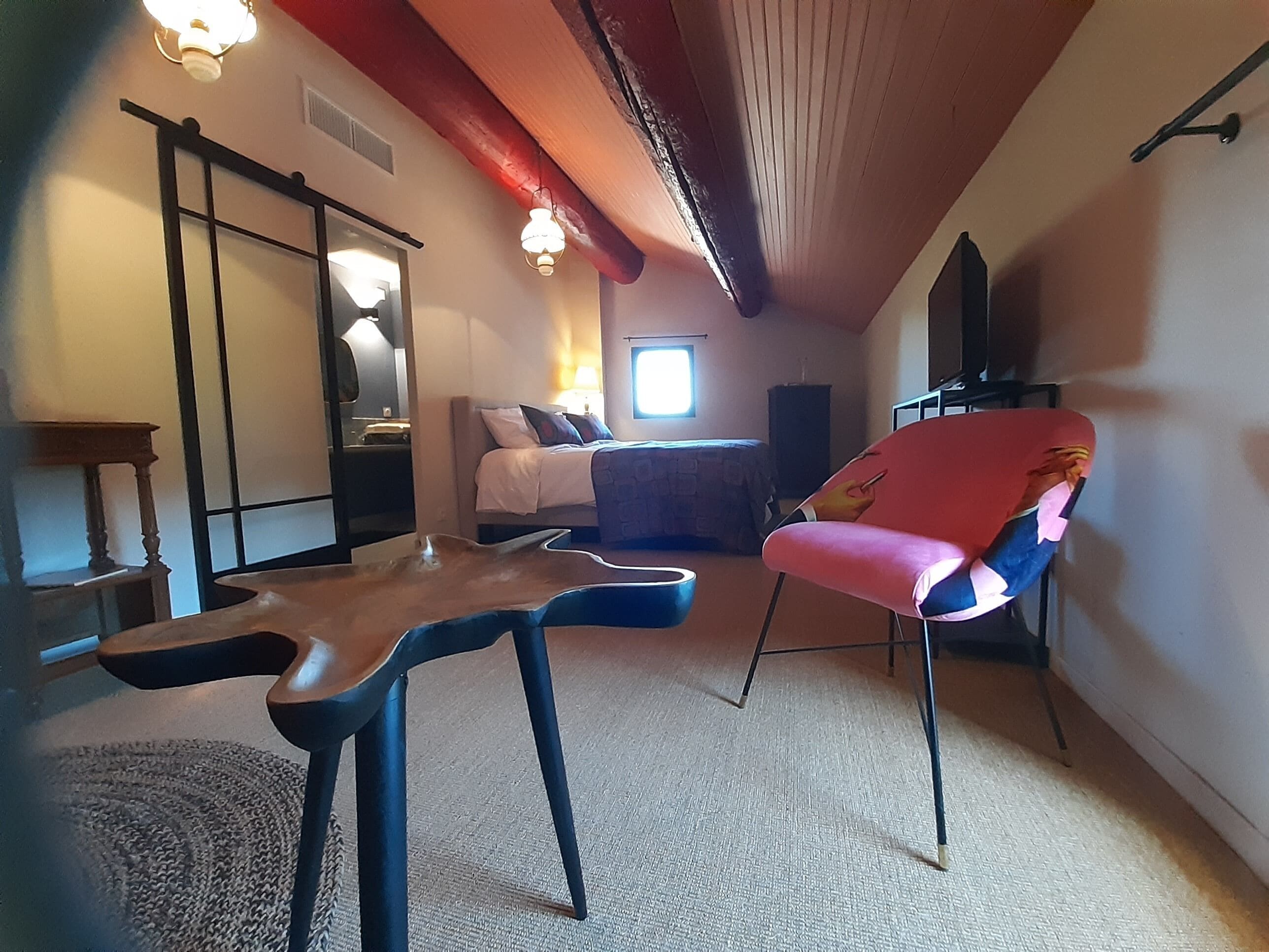 Um quarto aconchegante com uma cama, uma cadeira, uma mesa e um espelho.