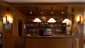 Uma área de bar com armários de madeira, prateleiras com garrafas e uma máquina de café.