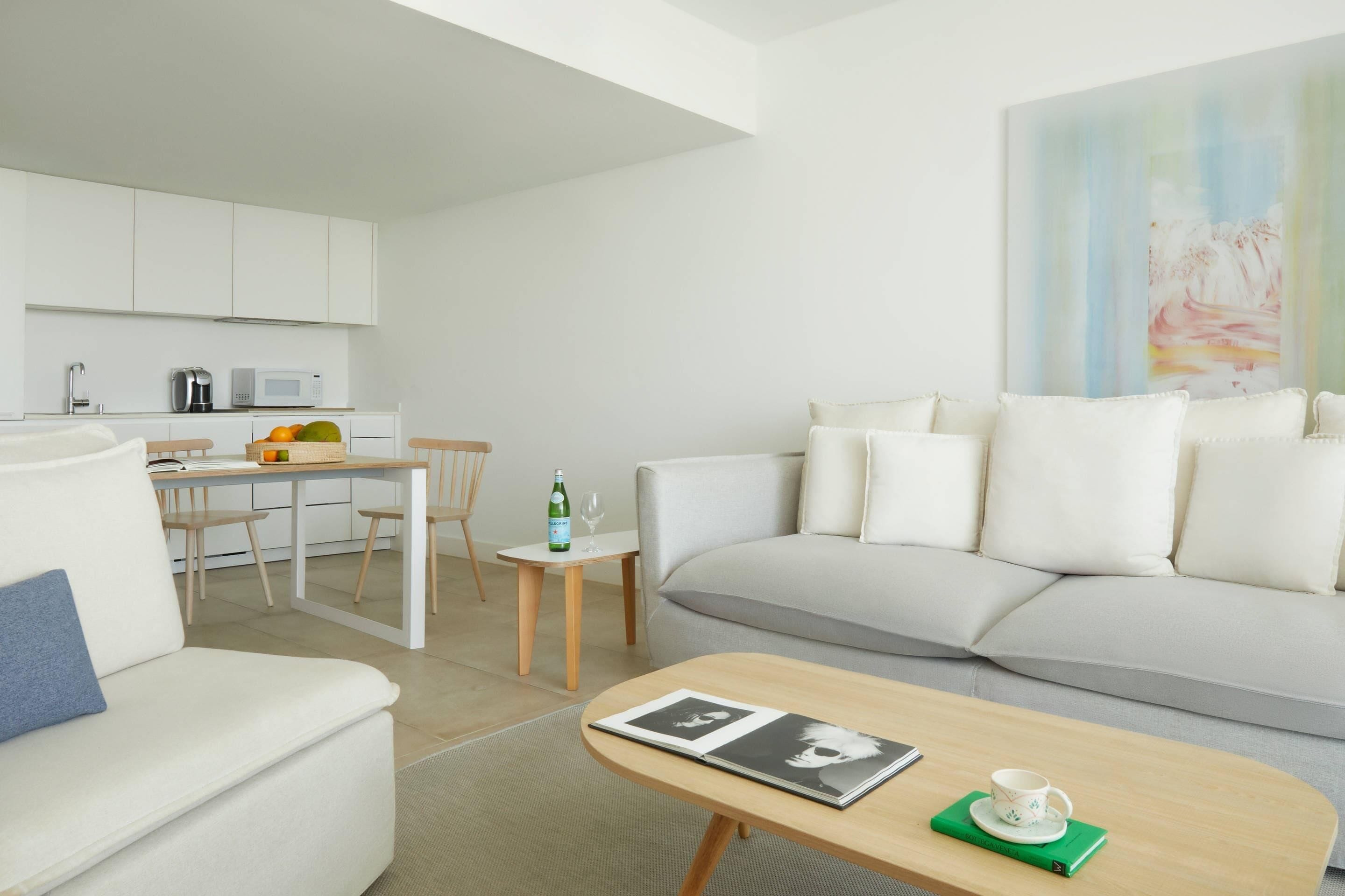 Uma sala de estar moderna com sofá, mesa de centro e área de jantar com mesa e cadeiras.