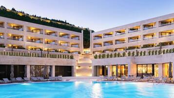 Hotel com piscina central, várias varandas e terraço ajardinado.