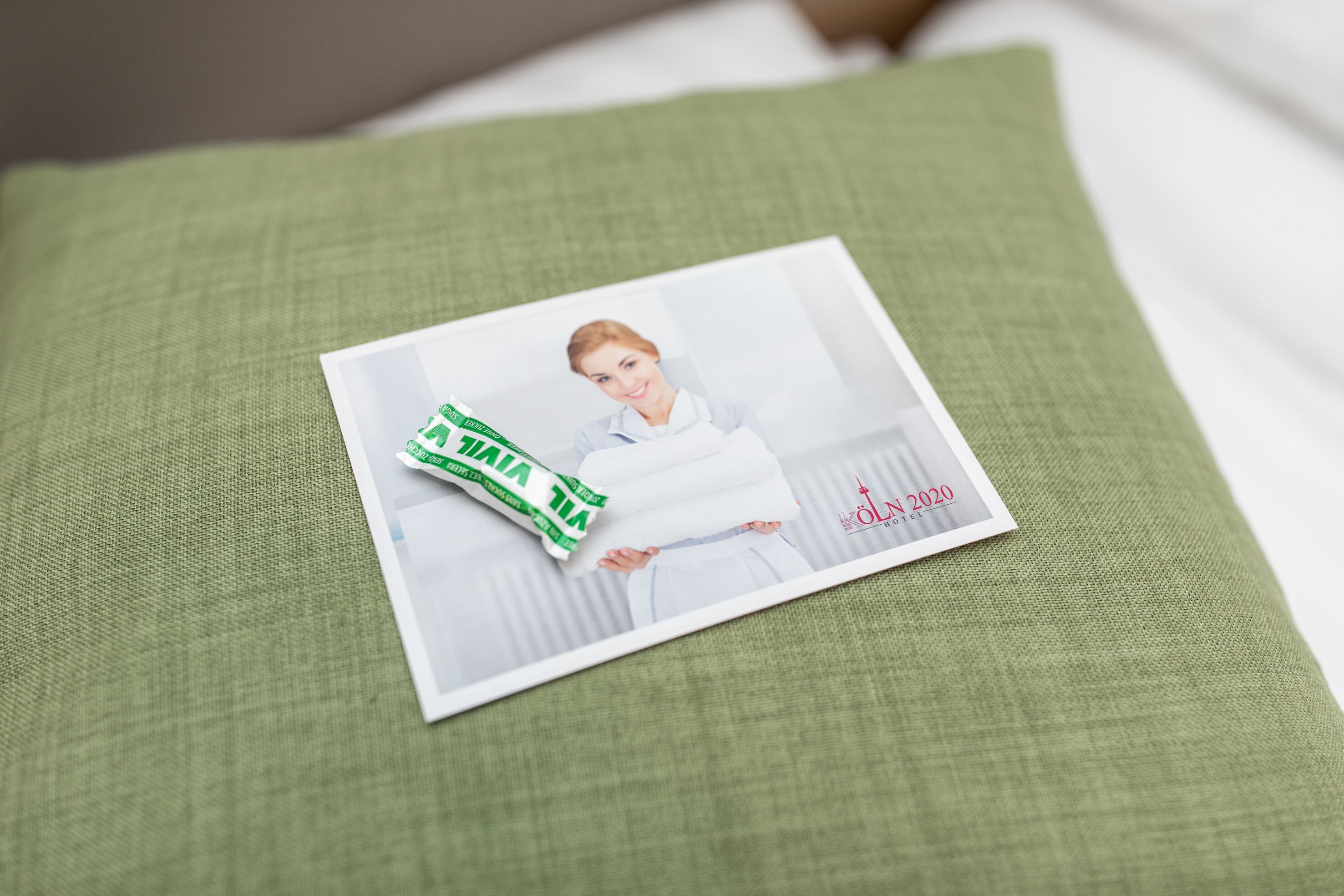 Uma cama com um travesseiro verde e uma fotografia de uma pessoa segurando uma toalha.
