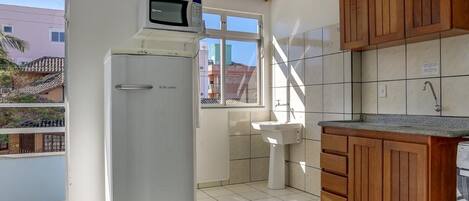 Cozinha com geladeira, pia, armários de madeira e janela.