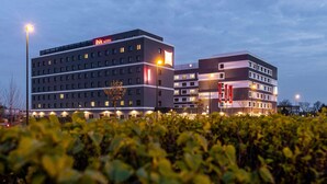 Um hotel com vários andares, um sinalizador 'ibis HOTEL' bem visível e uma fachada bem iluminada.