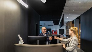 Balcão de recepção com um homem e uma mulher conversando.