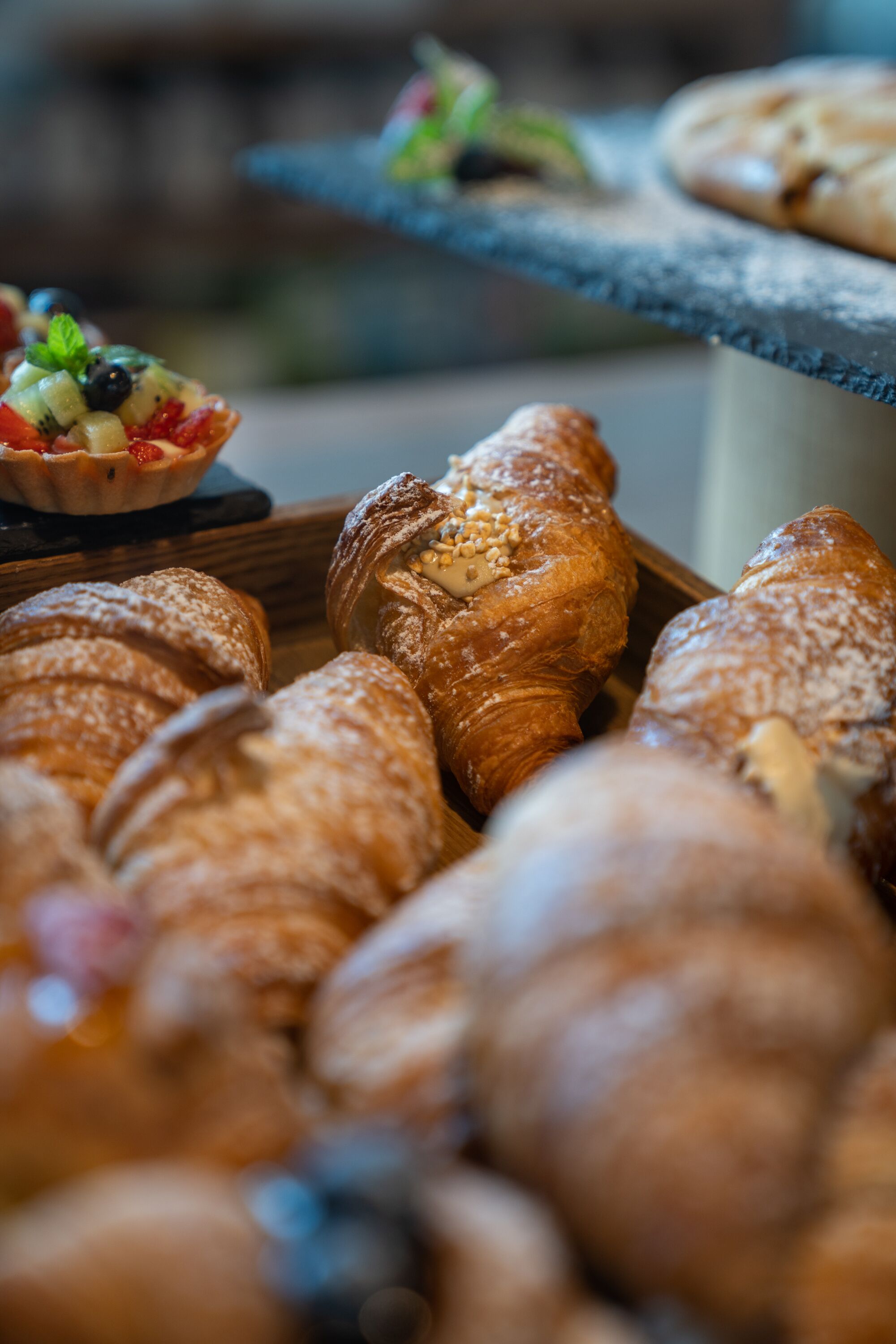 Diversos pastéis e sobremesas expostos sobre uma mesa de madeira.
