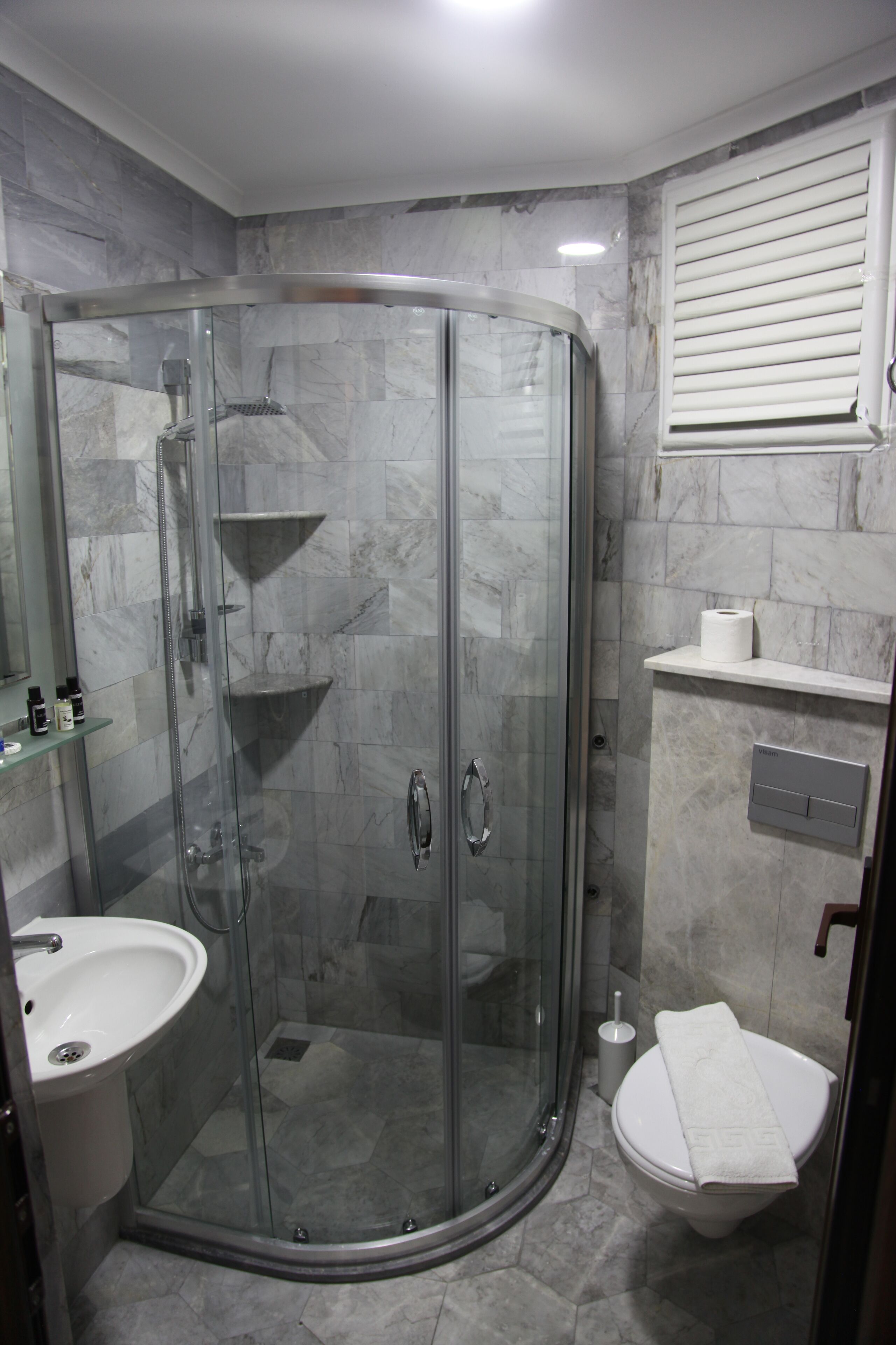 Uma casa de banho moderna com chuveiro em cabine de vidro, pia e sanita.