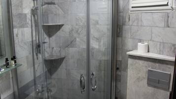 Uma casa de banho moderna com chuveiro em cabine de vidro, pia e sanita.
