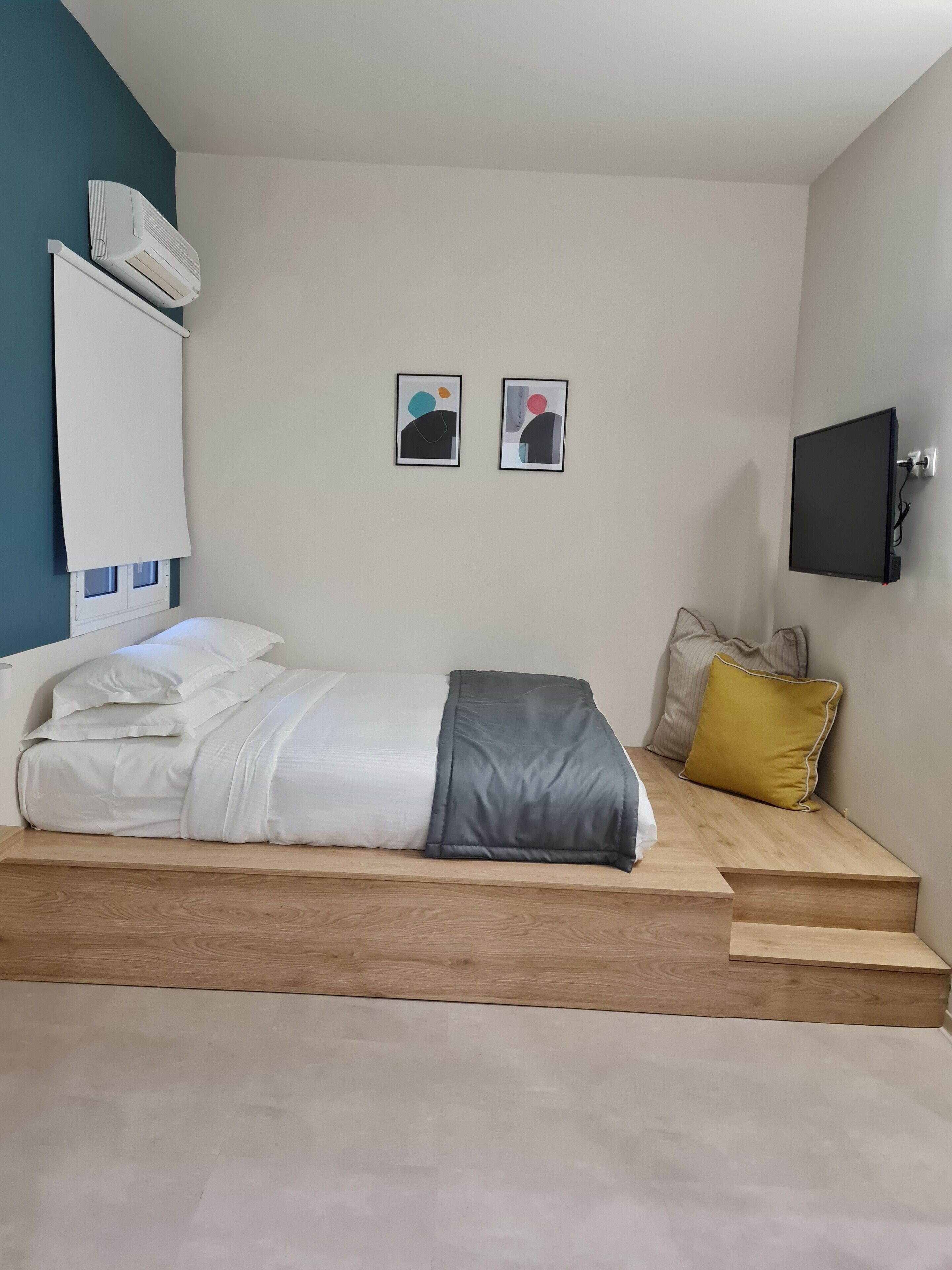 Quarto com cama, televisão e duas imagens emolduradas na parede.